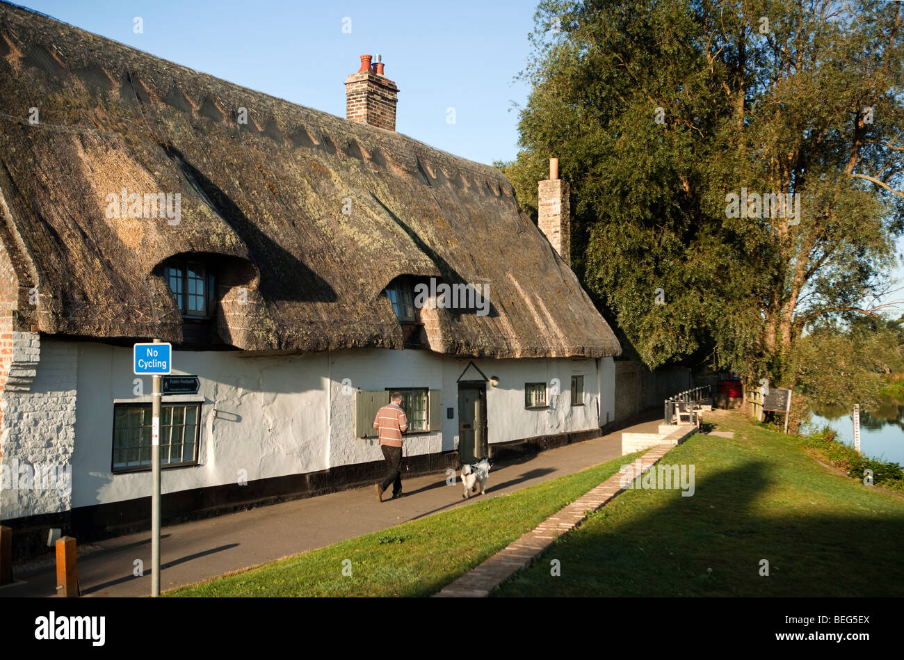 England, Cambridgeshire, Hemingford Grey, Man walking dog past idyllic ...