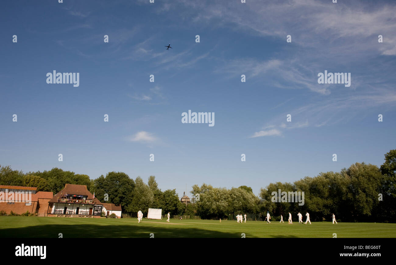 Players in a cricket match are oblivious to a passing airliner that ...
