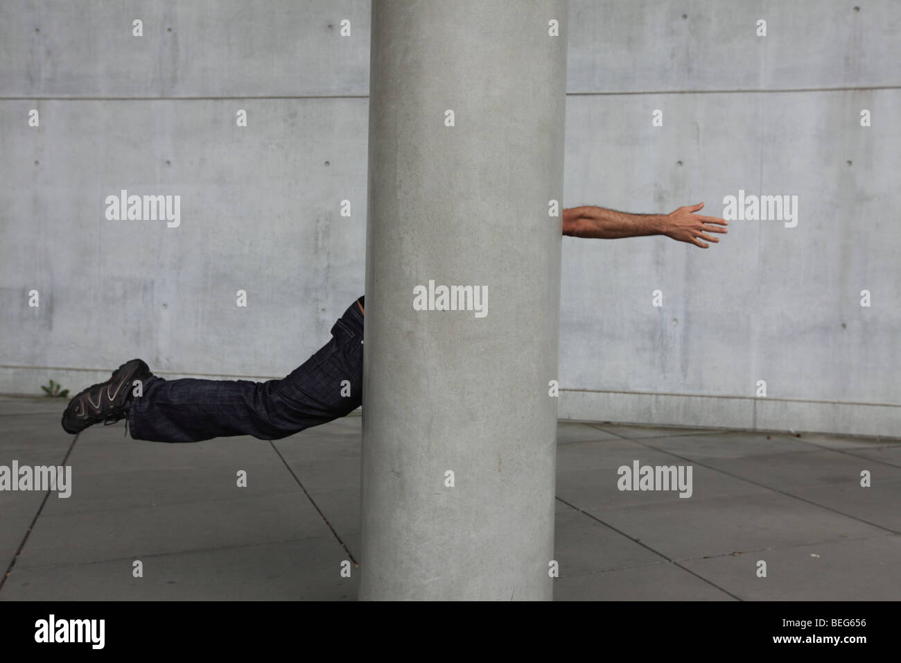Person hiding behind Pillar revealing a leg and an arm Stock Photo - Alamy