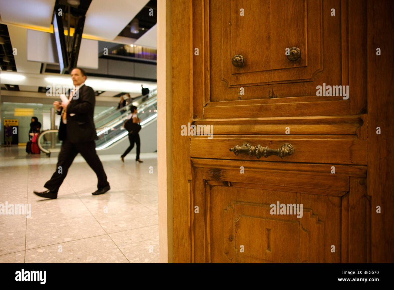 Passing passengers walk past the Paul Smith château door at Heathrow ...