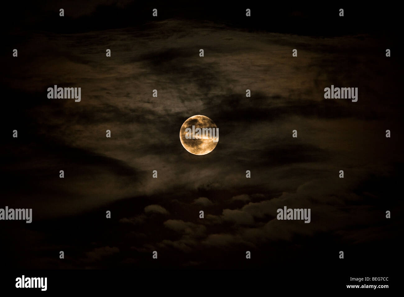 Full moon behind clouds warm yellow color Stock Photo - Alamy