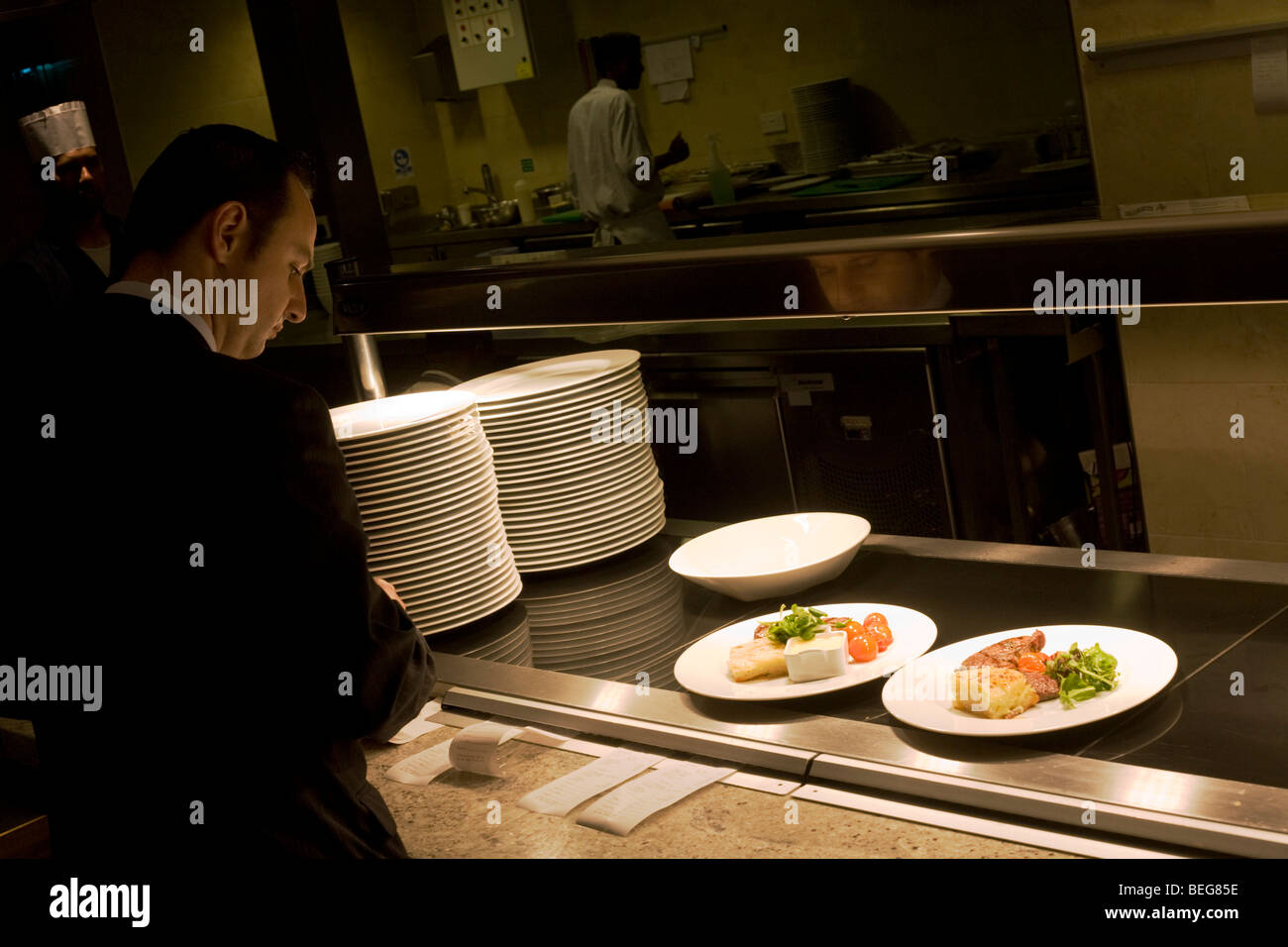 A Head Waiter is about to take finished dishes during service in the ...