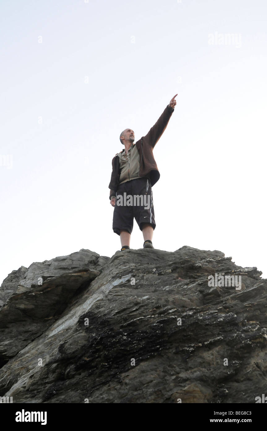 A man on a rock pointing at something Stock Photo - Alamy