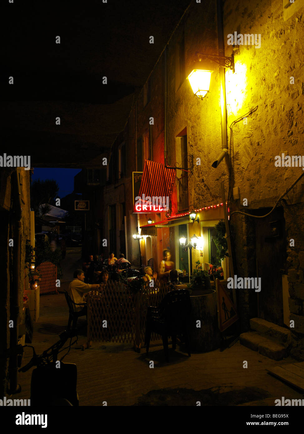 A pavement restaurant lit by a street lamp at night in Sospel in ...