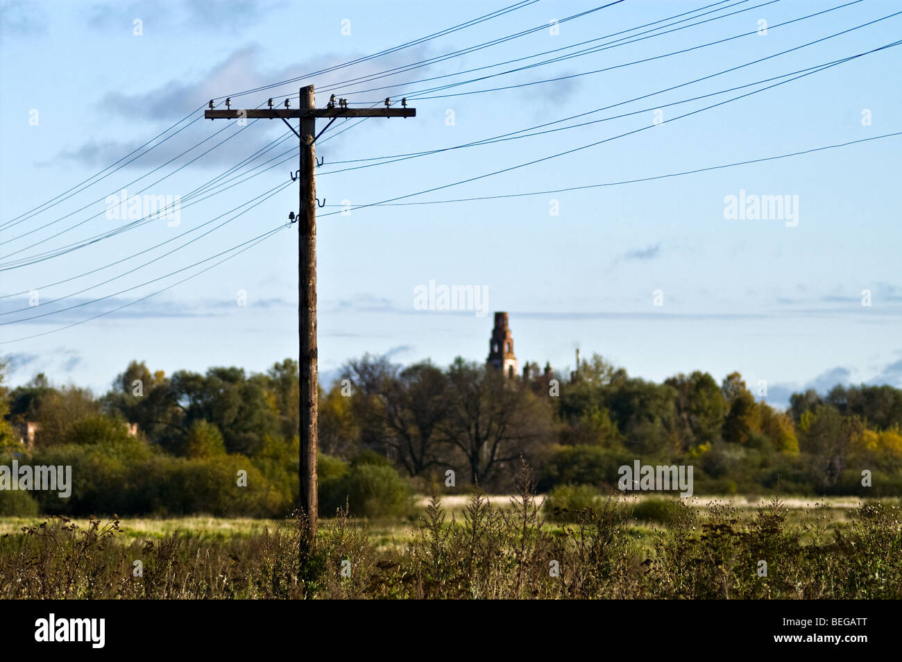 Wooden pole of power transmission line with ruins of a church at the ...