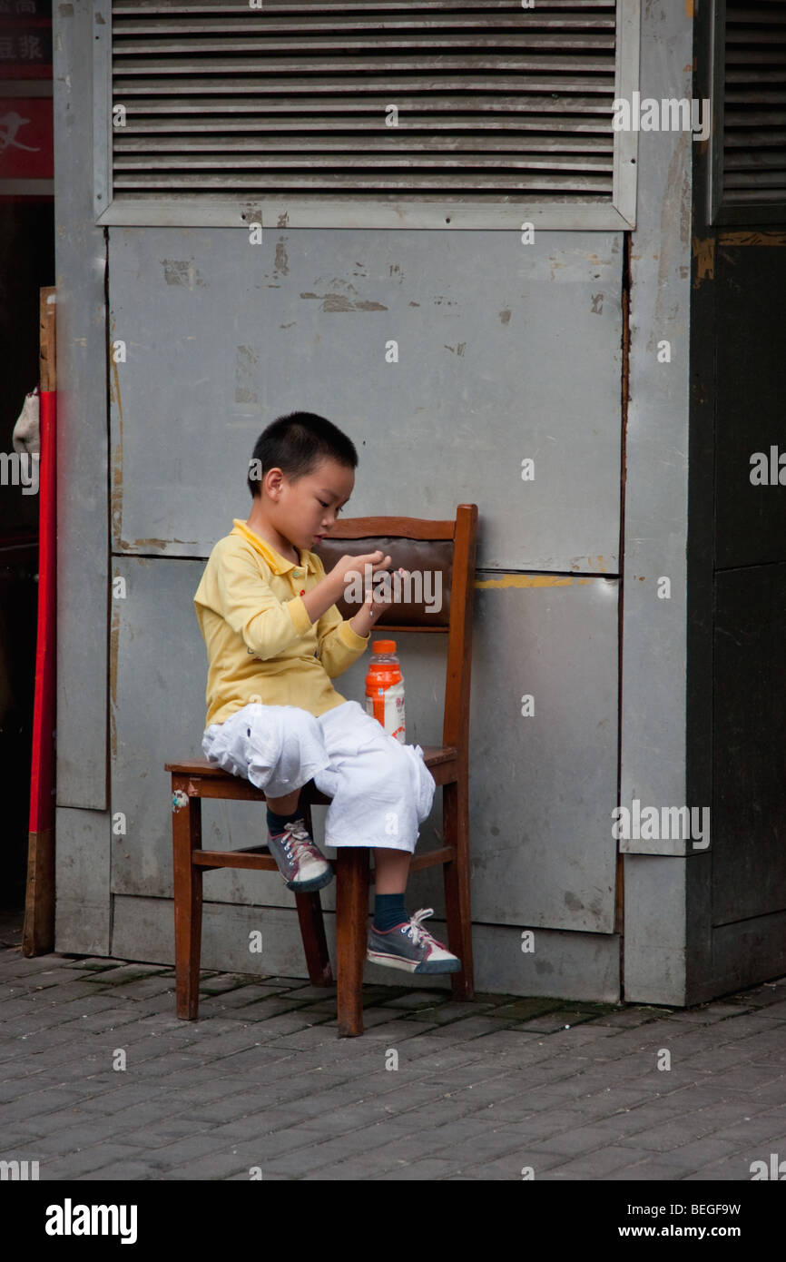 Child sitting on a chair in the street in Shanghai China Stock Photo ...