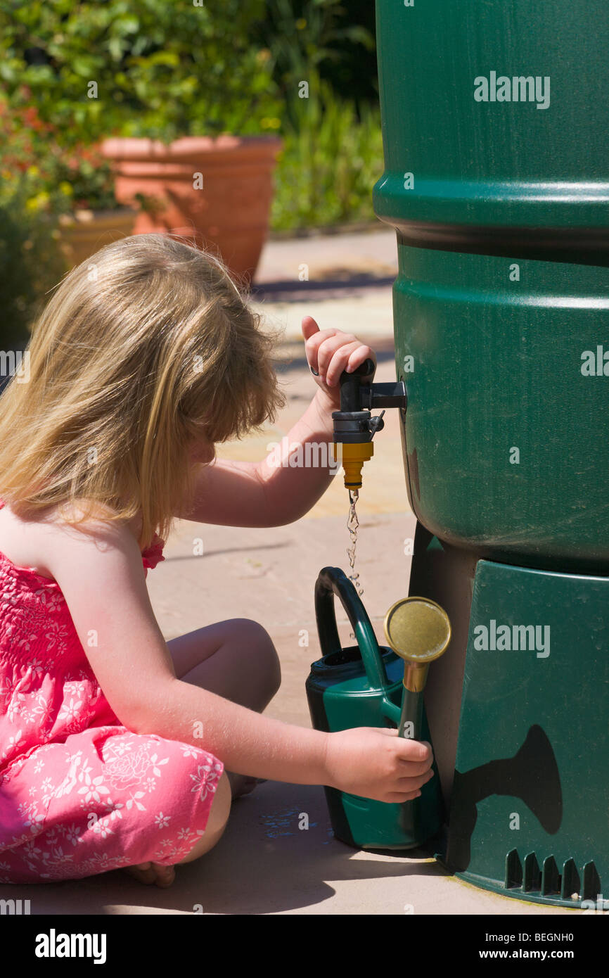 Young girl collecting water in a watering can from a "water butt Stock ...