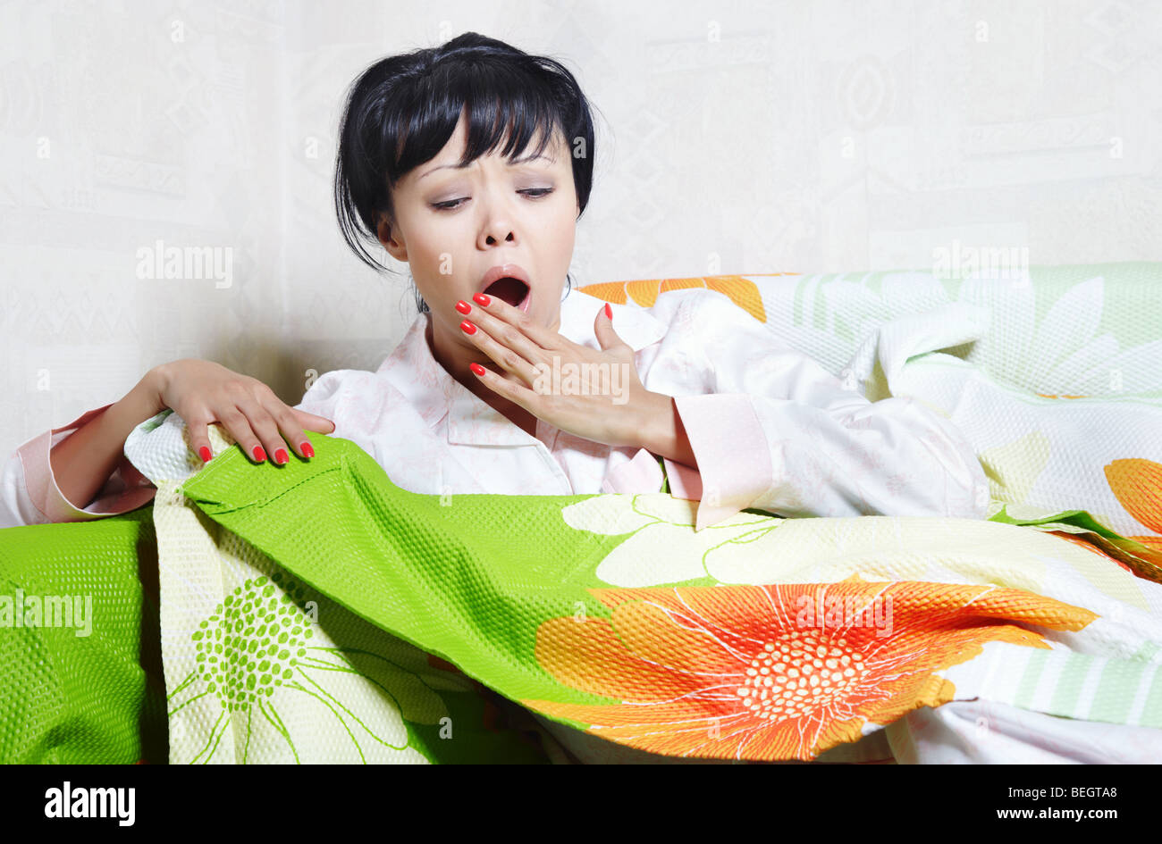 Yawning lady on the bed covered by colorful blanket Stock Photo - Alamy