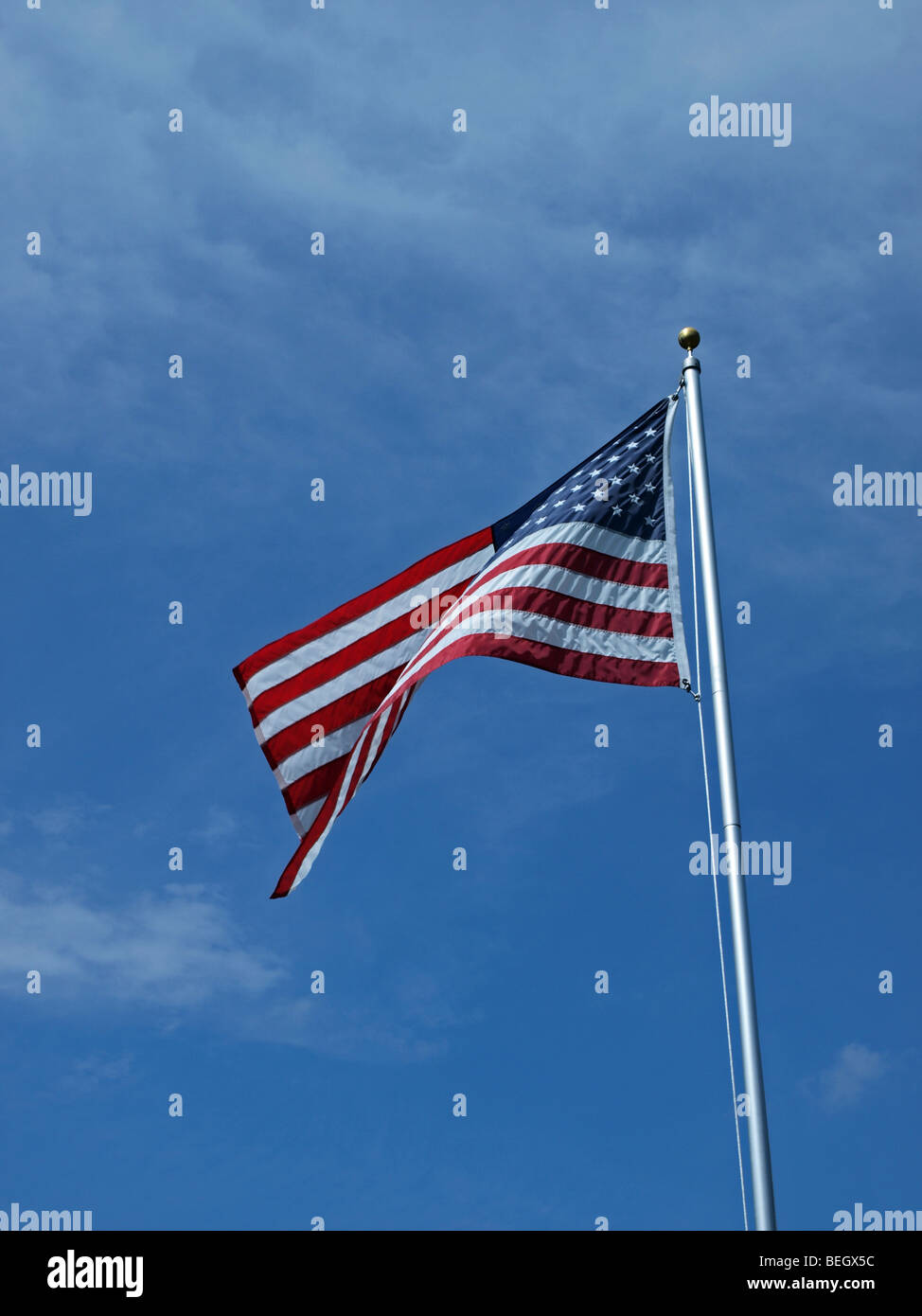 USA flag "old glory" flowing on top of tall flagpole with blue sky ...