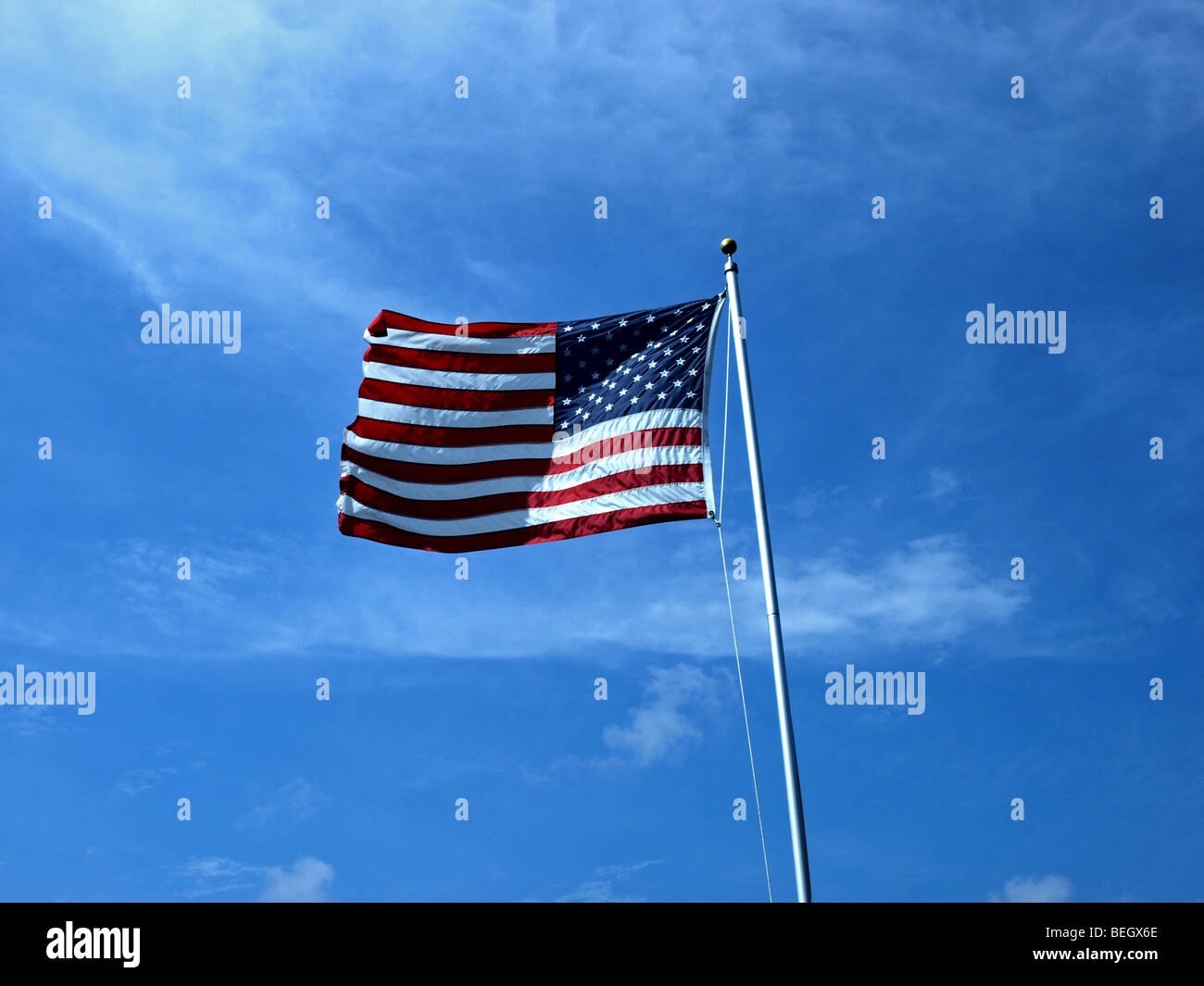 USA flag "old glory" flowing on top of tall flagpole with blue sky ...