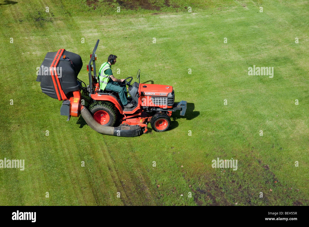 Man using petrol driven ride-on lawn mower to cut large area of grass ...