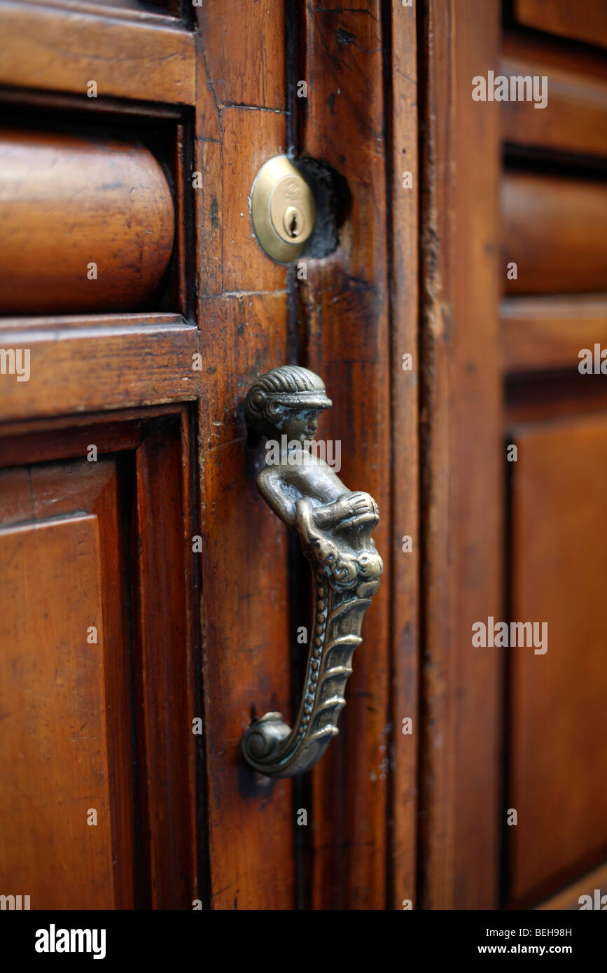 An ornate door knocker in the shape of a child on a wooden door in ...
