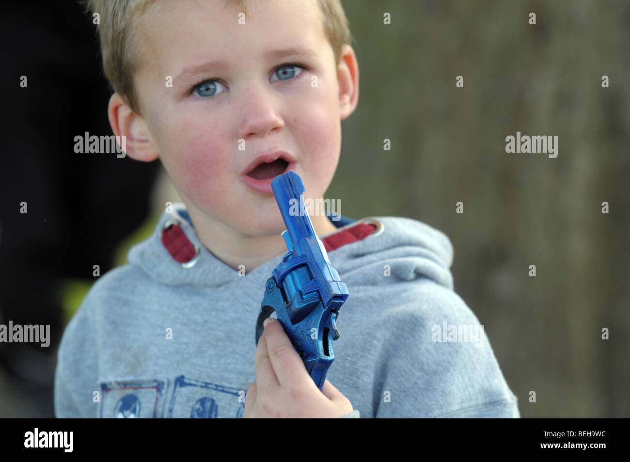 A young boy holds a toy gun near to his mouth Stock Photo - Alamy