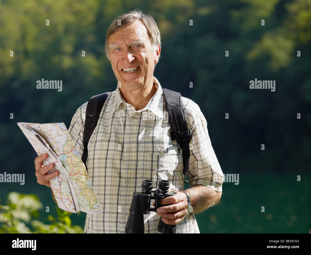 senior hiker holding map and binoculars and looking at camera. Copy ...