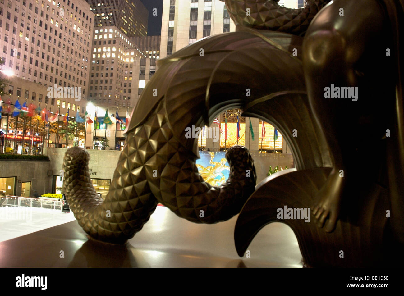 Close-up of a statue with buildings lit up at night in the background ...