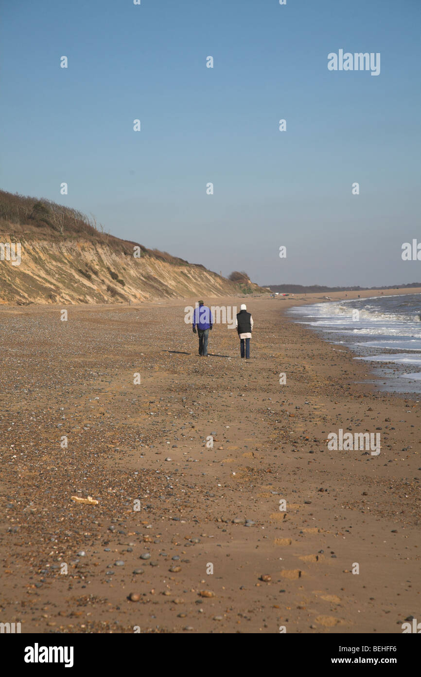 Two people walking on beach. Dunwich beach and cliffs, North Sea coast, Suffolk, East Anglia ...