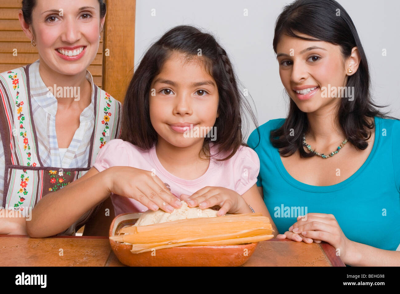 Portrait of a girl preparing bread with her mother and sister in the ...