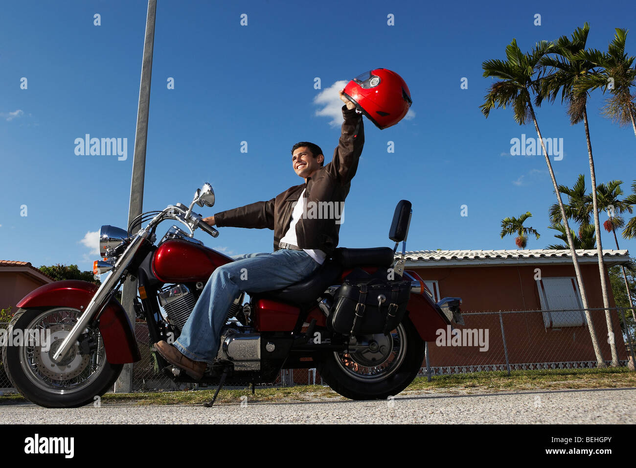 Side profile of a mid adult man sitting on a motorcycle and raising his ...