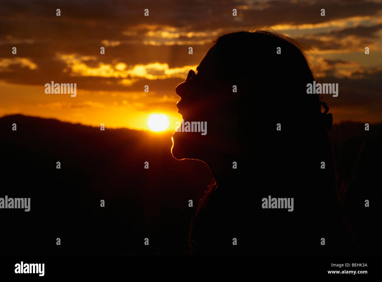 Silhouette of a woman pretending to eat sun at dusk Stock Photo - Alamy