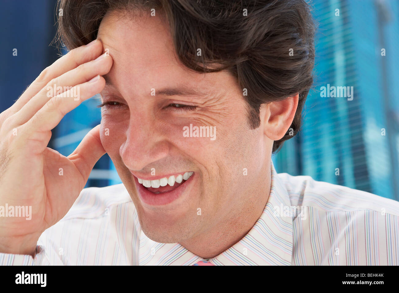 Close-up of a businessman smiling with his hand on his forehead Stock ...