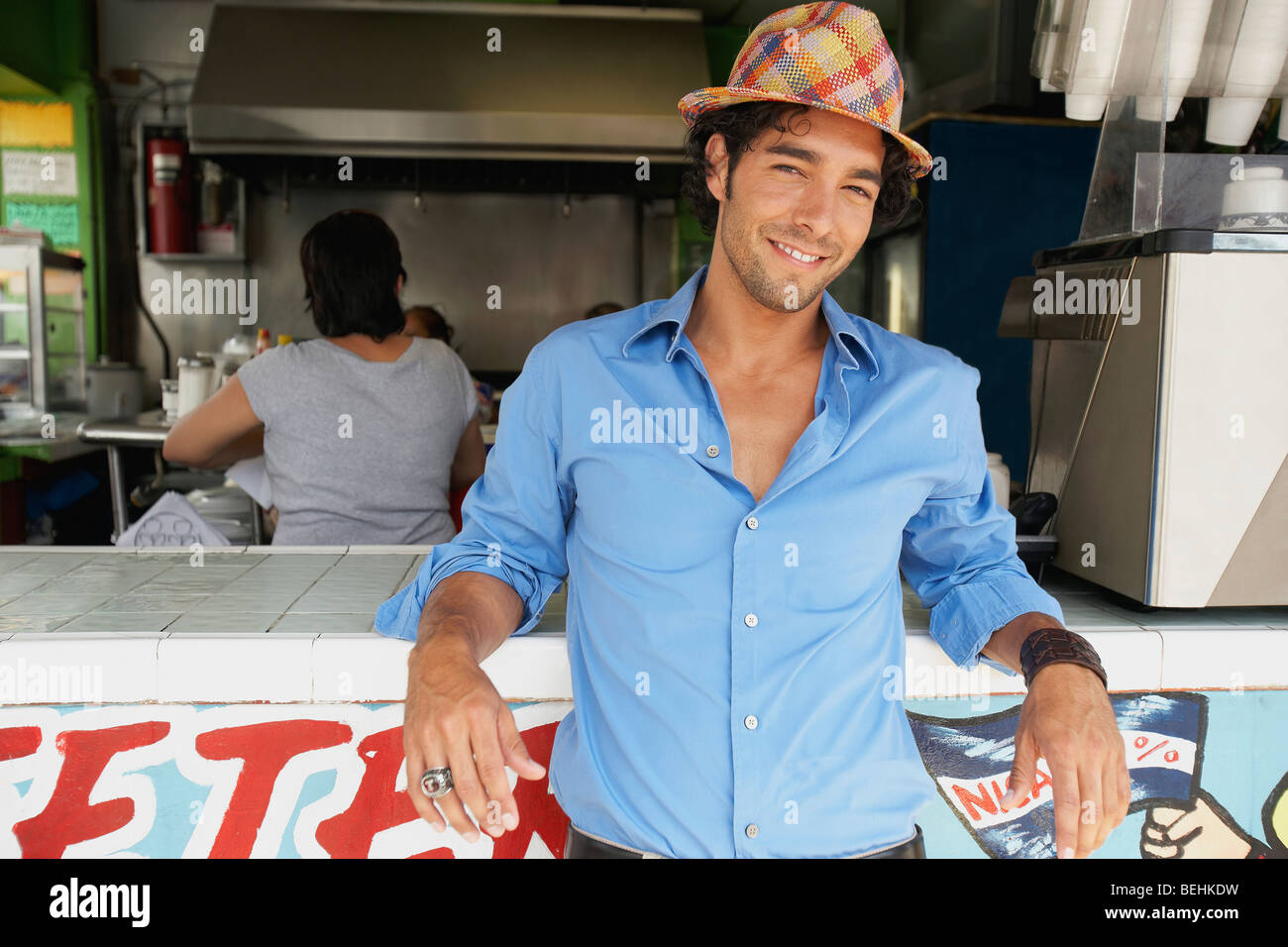Portrait of a young man leaning against a bar counter of a juice bar ...