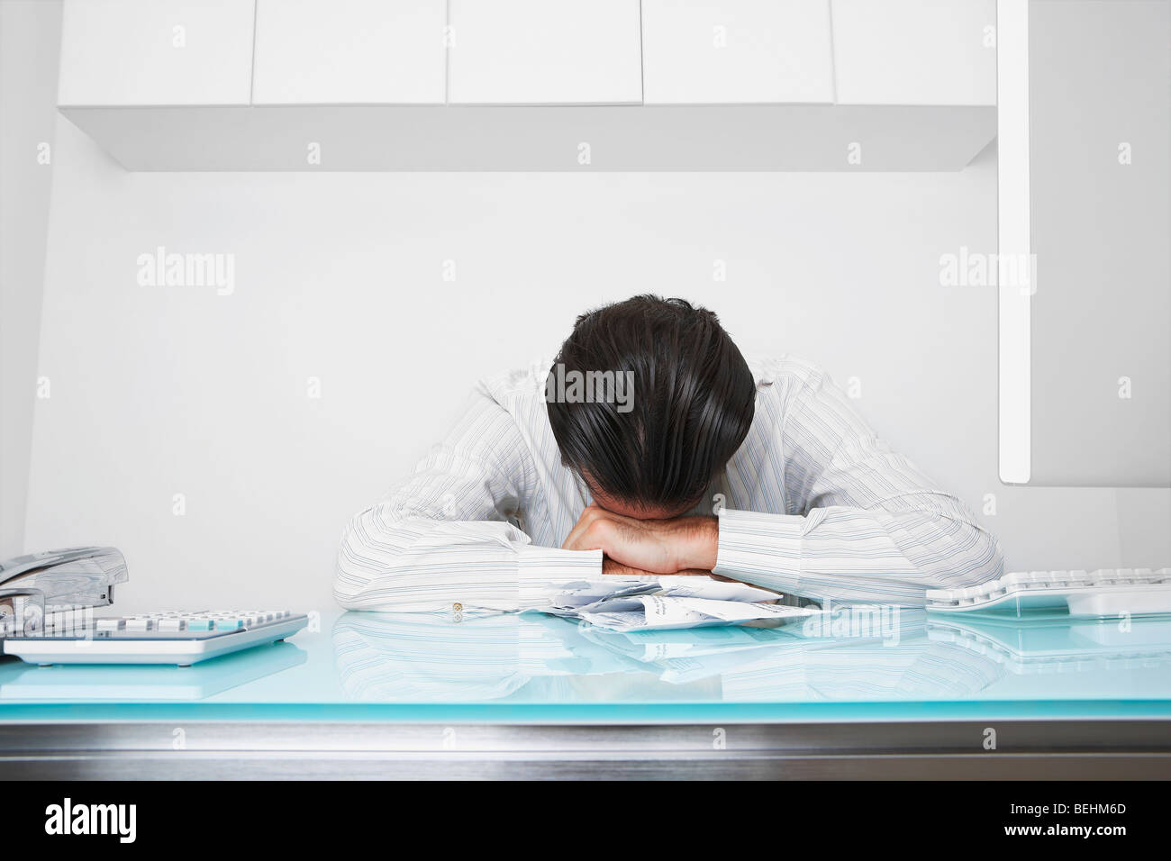 Businessman resting his head on his hands at a desk in an office Stock ...