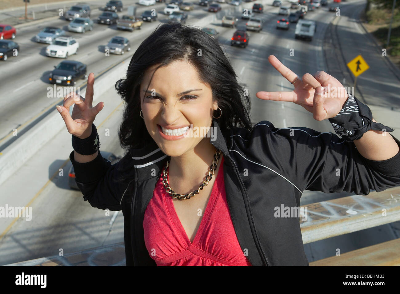 Portrait of a young woman showing a peace sign and smiling Stock Photo ...