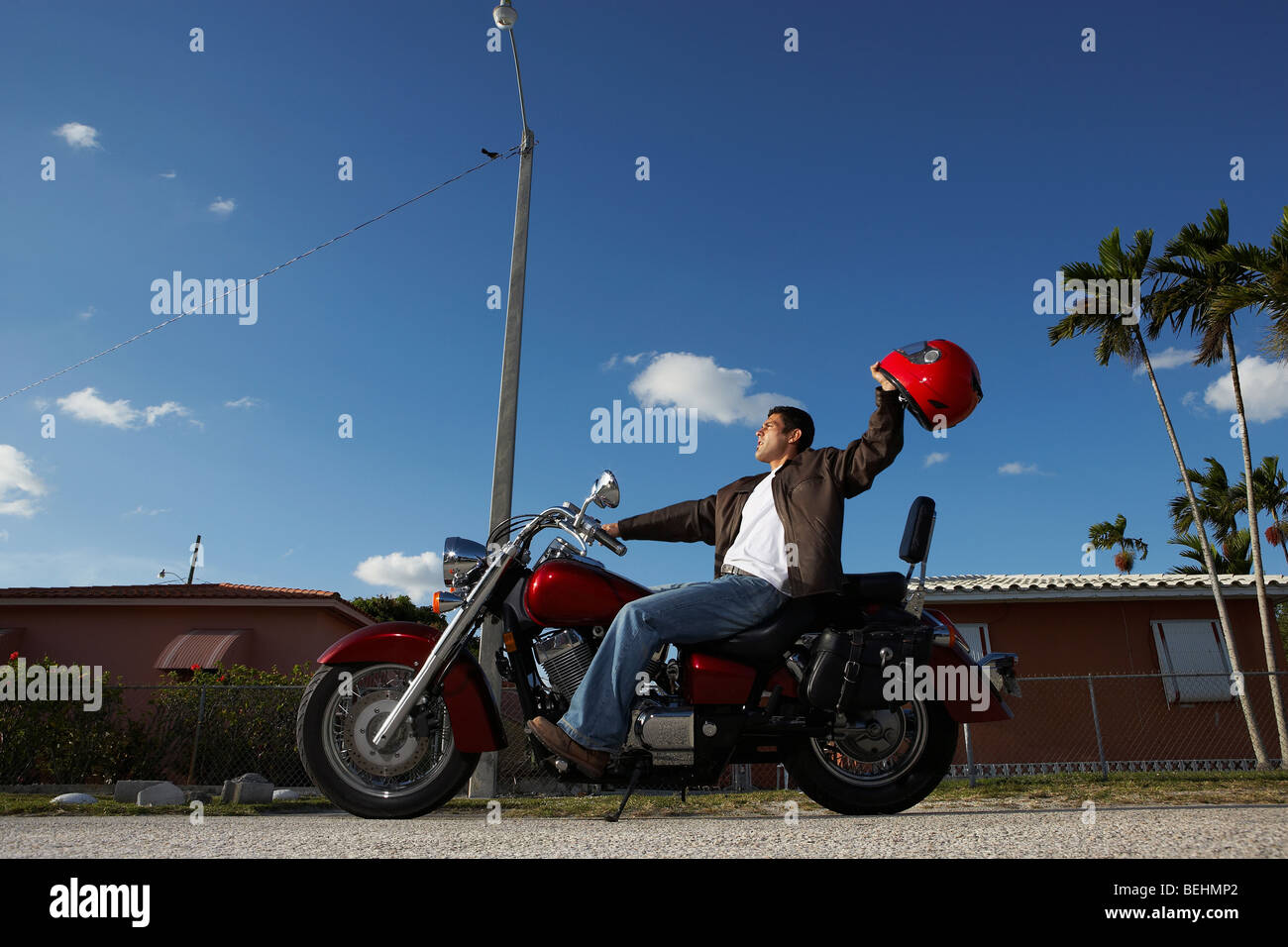 Side profile of a mid adult man sitting on a motorcycle and raising his ...