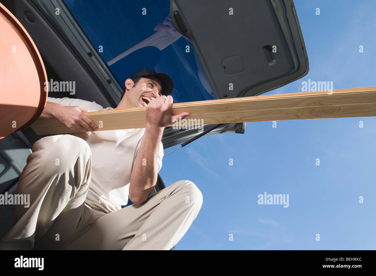 Man holding a wooden plank and laughing Stock Photo - Alamy