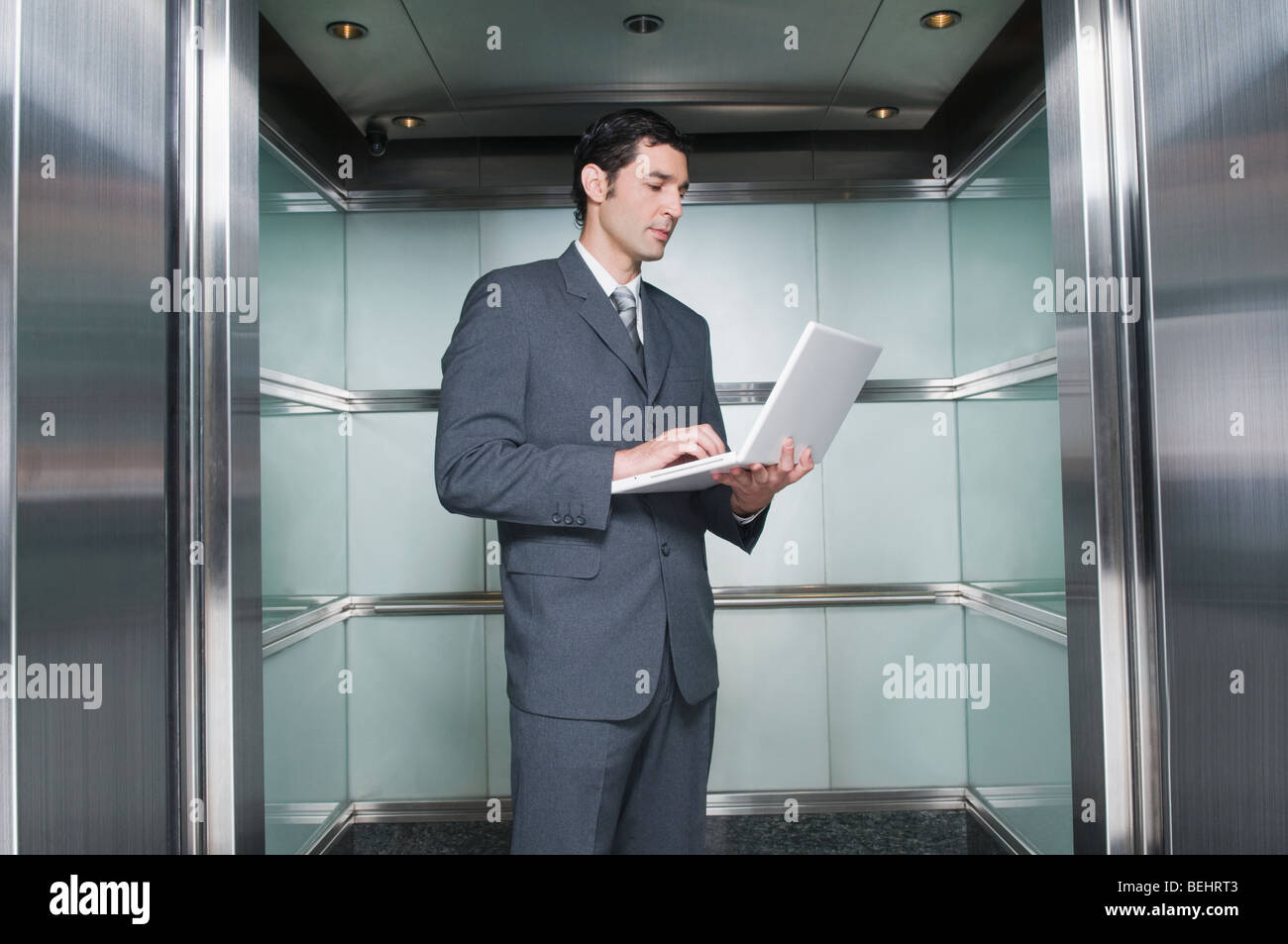 Businessman working on a laptop in an elevator Stock Photo - Alamy