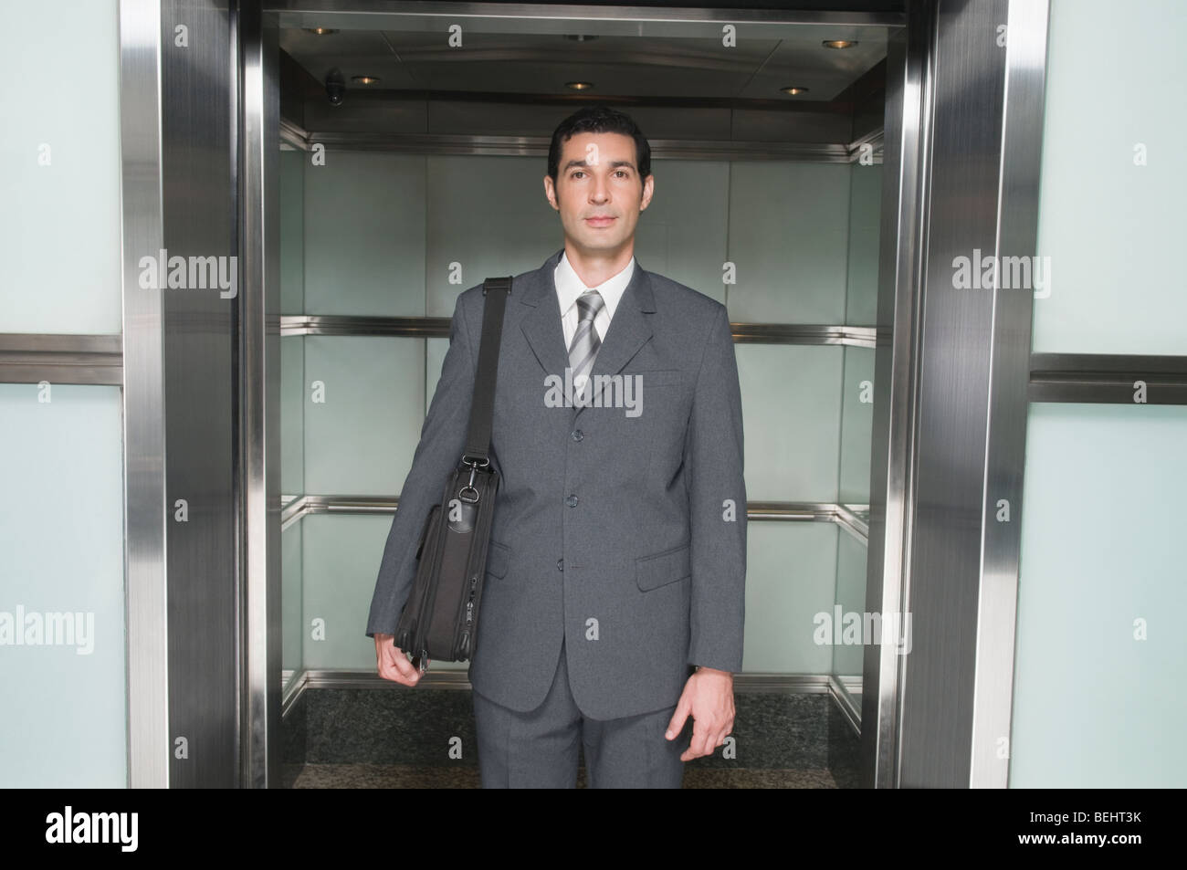 Businessman stepping out of an elevator Stock Photo - Alamy