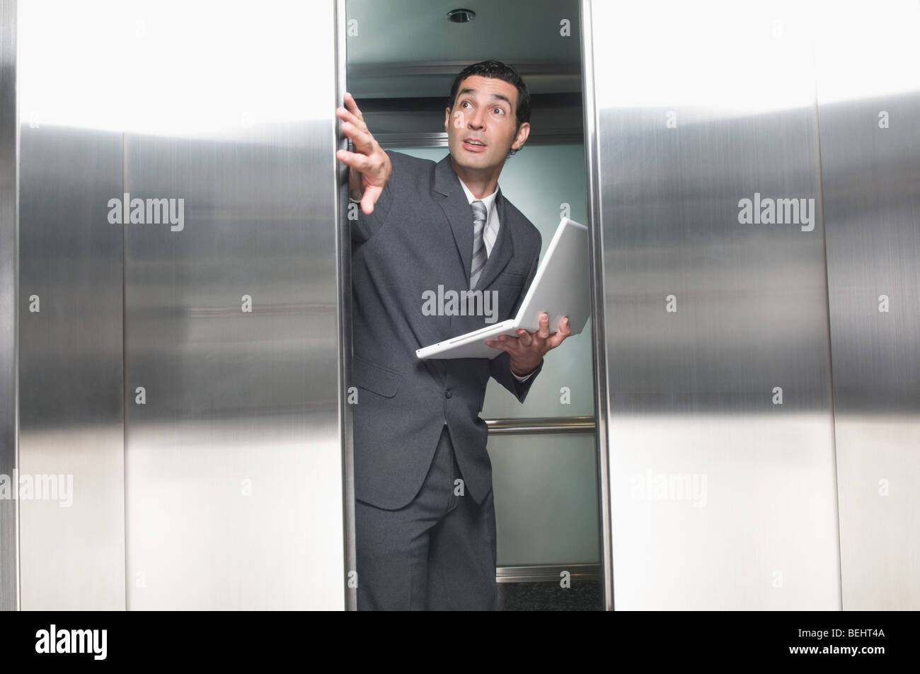 Businessman holding a laptop in an elevator Stock Photo - Alamy