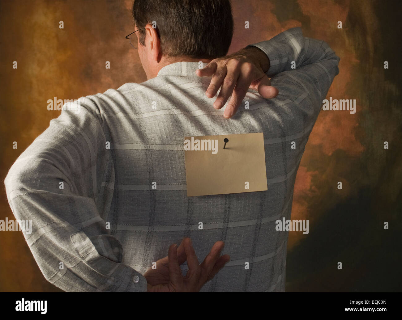 man reaching for note nailed to his back Stock Photo - Alamy
