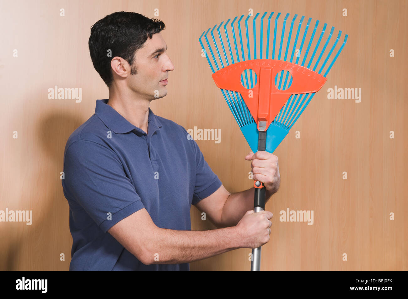 Man holding a rake Stock Photo - Alamy