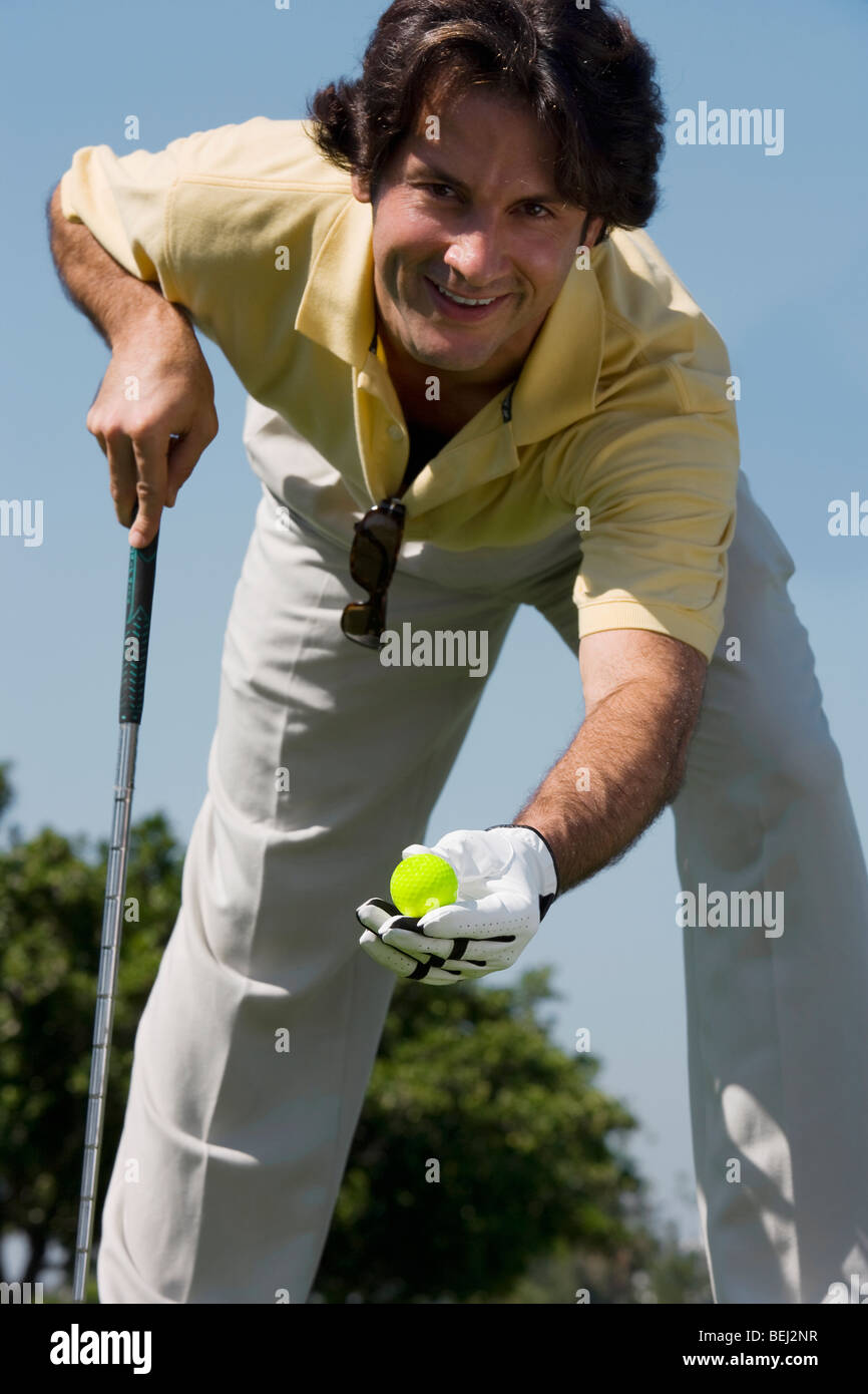 Portrait of a mid adult man holding a golf ball and a golf club Stock ...