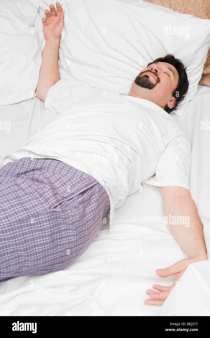 Mid adult man sleeping on the bed Stock Photo - Alamy