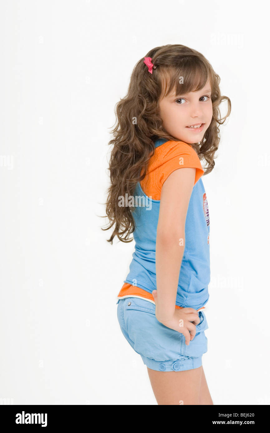 Side profile of a girl standing with her hand on her hip and smiling ...