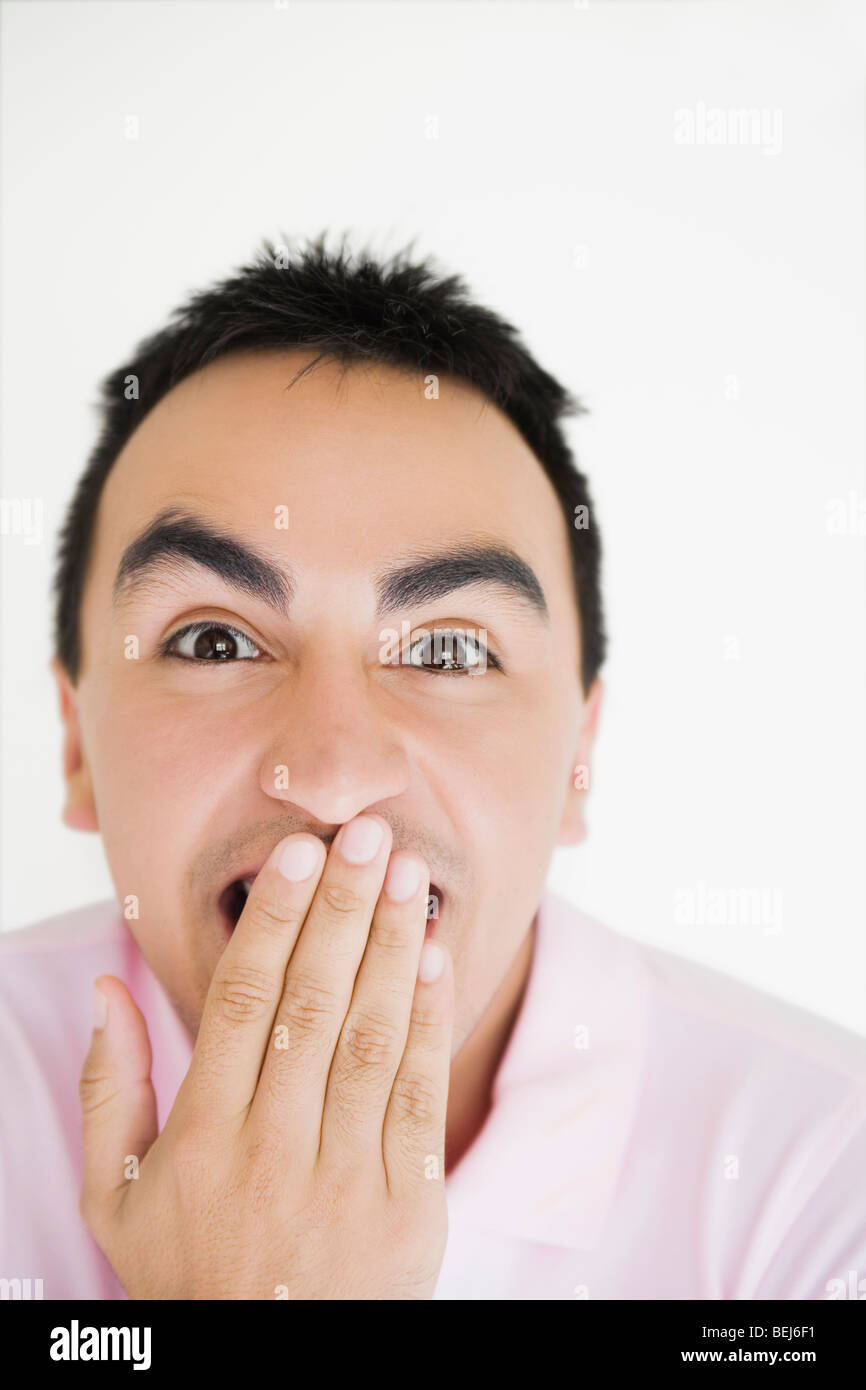 Portrait Of A Young Man Covering His Mouth With His Hand And Smiling