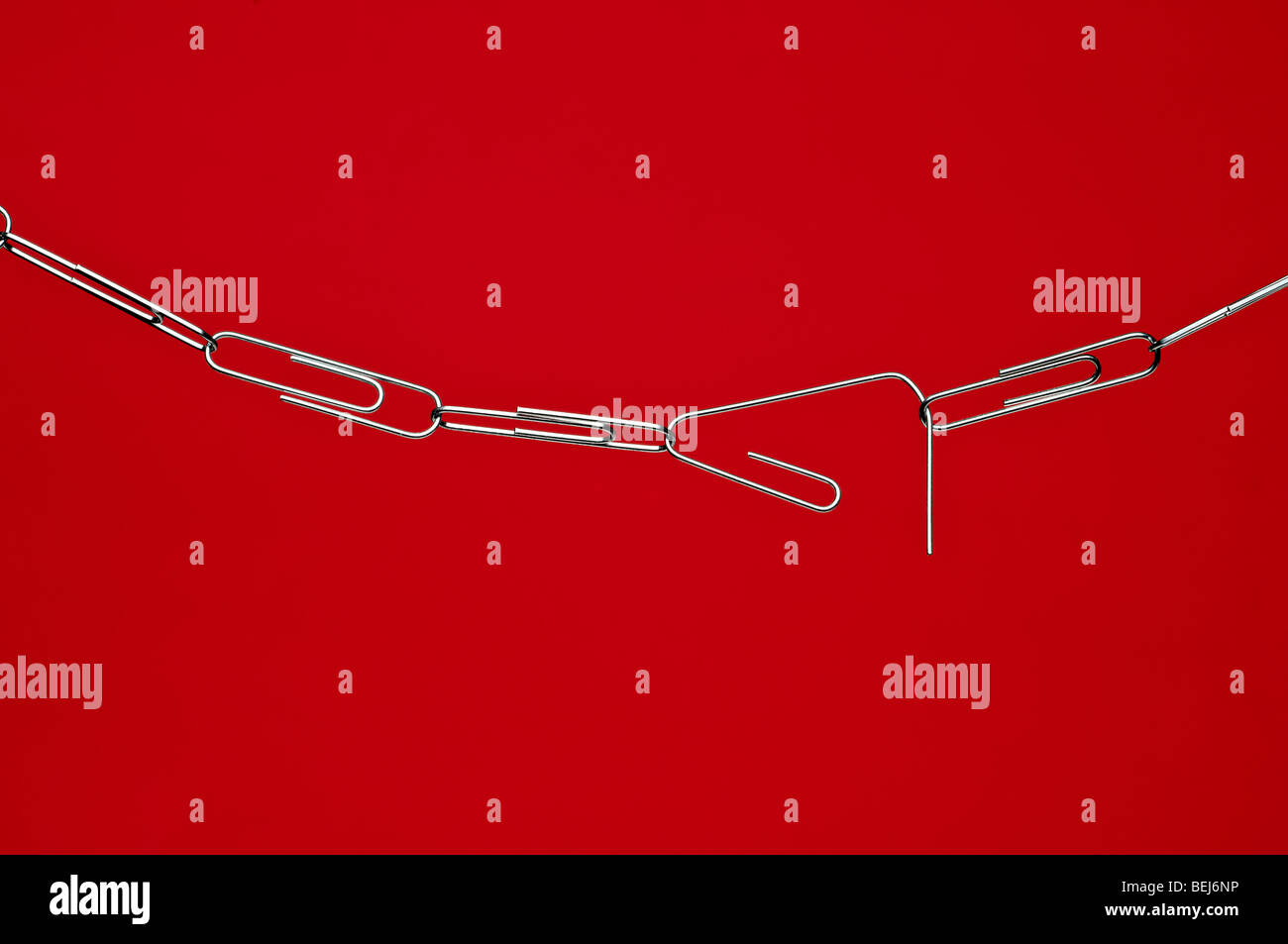 horizontal breaking paperclip chain on red Stock Photo - Alamy