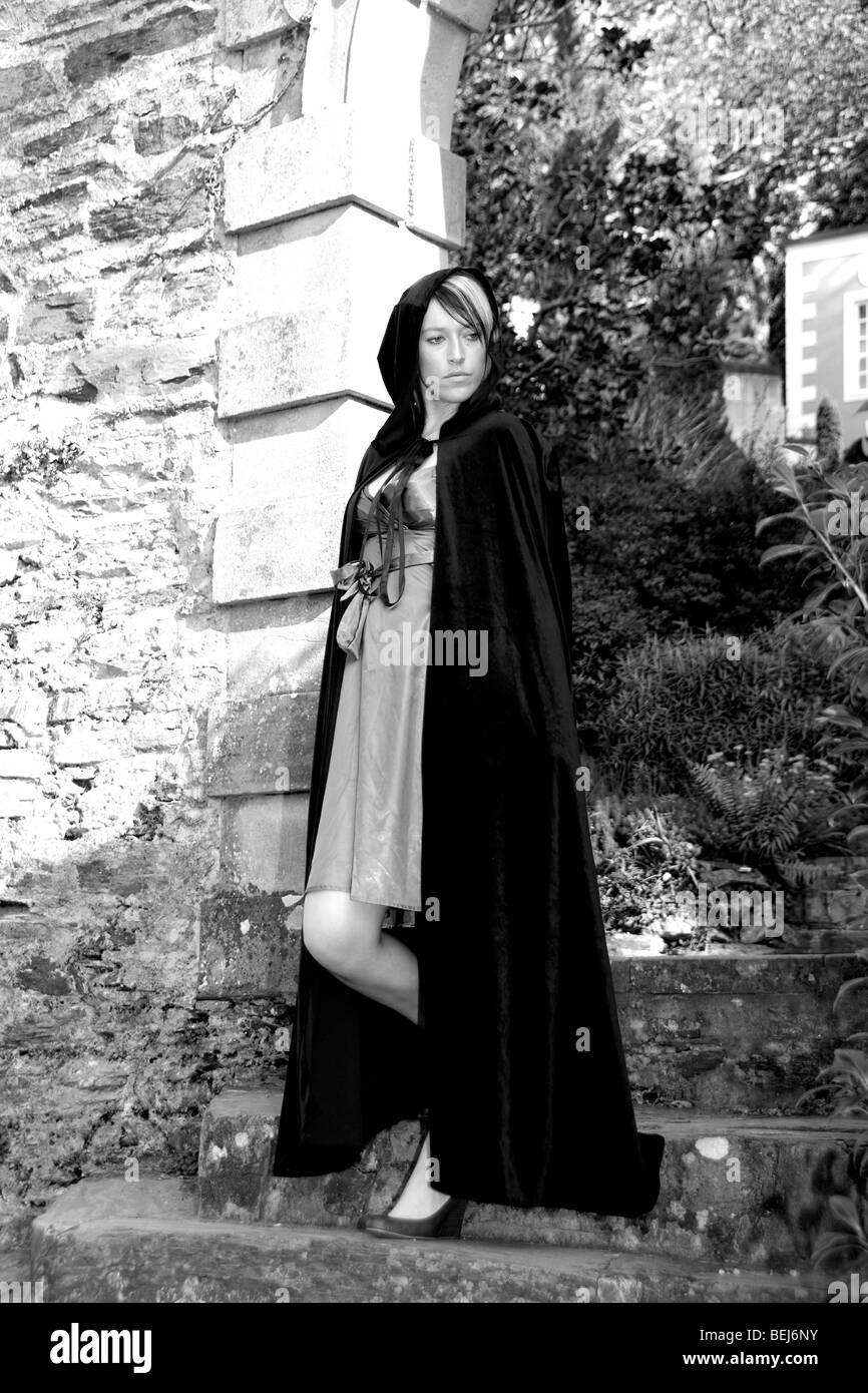 Pretty young woman in a green dress and velvet cloak in the gardens at ...