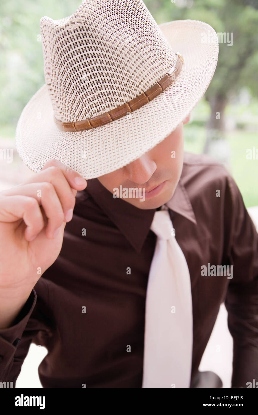 Close-up of a young man tipping hat Stock Photo - Alamy