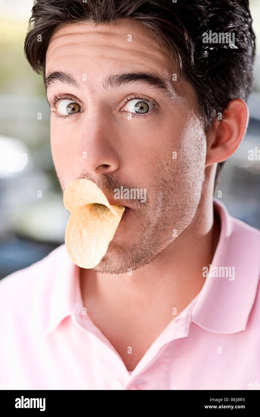 Portrait of a young man eating potato chips Stock Photo - Alamy
