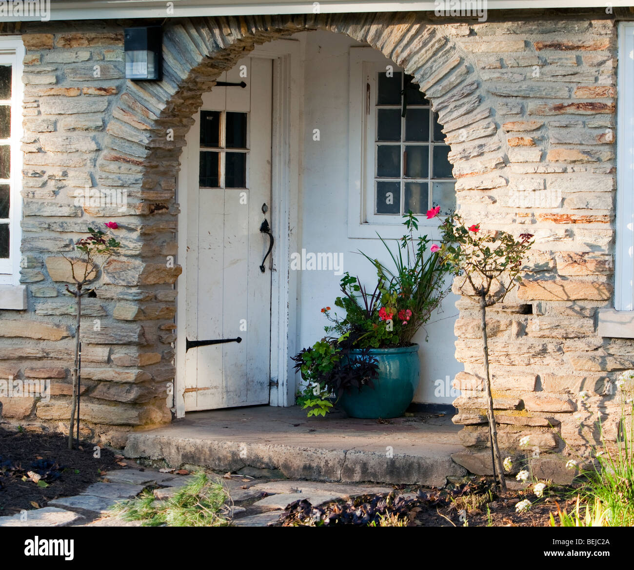 A recessed entrance with an archway and potted plants into an old ...