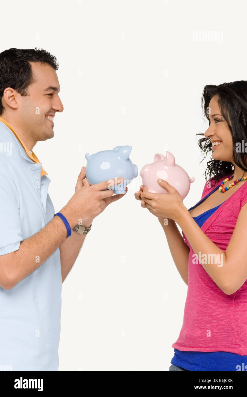 Side profile of a young couple holding piggy banks and smiling Stock ...