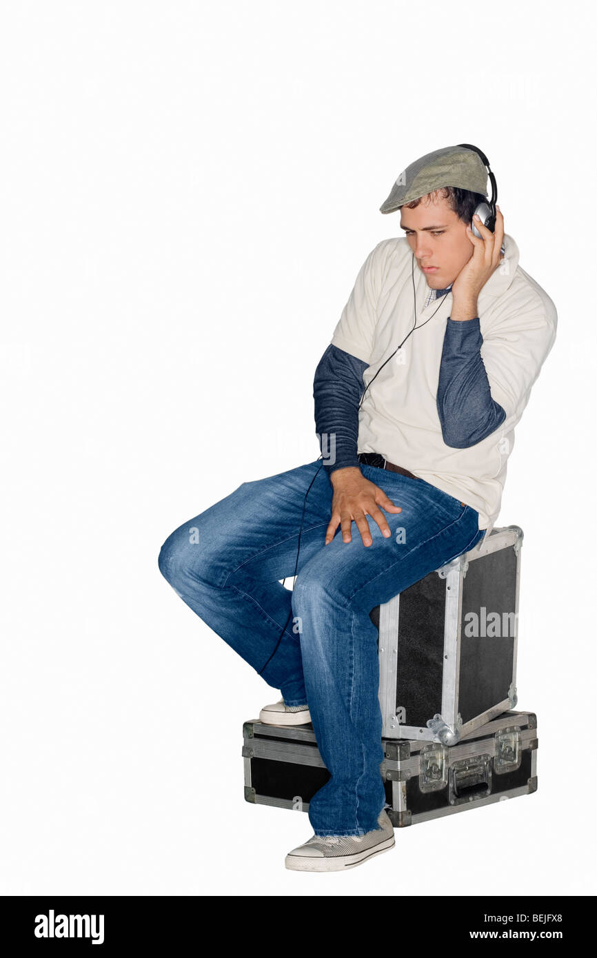 Young man sitting on trunks and listening to music Stock Photo - Alamy