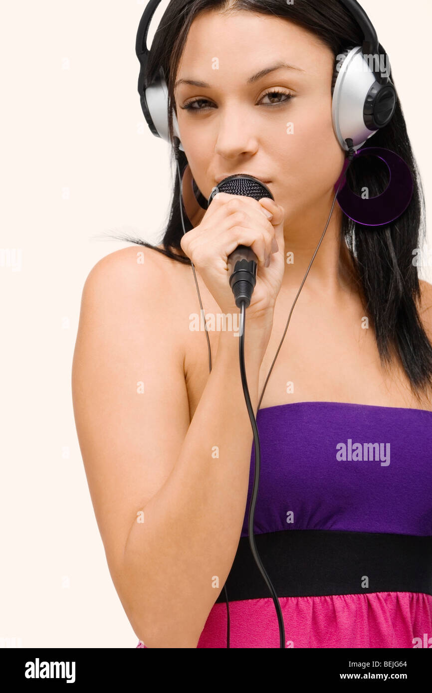 Portrait of a young woman singing into a microphone Stock Photo - Alamy