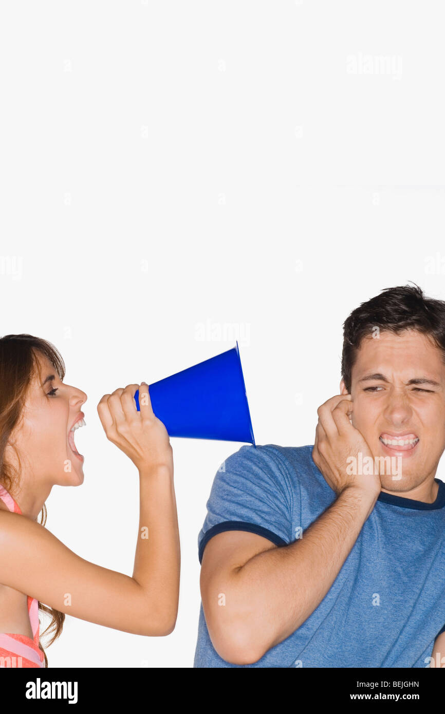 Side profile of a young woman shouting with a megaphone into a young ...