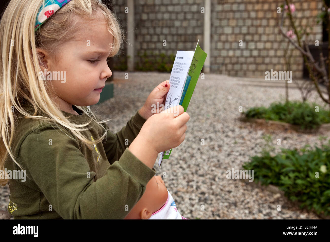 Nina with reading a book to her doll at home Stock Photo - Alamy