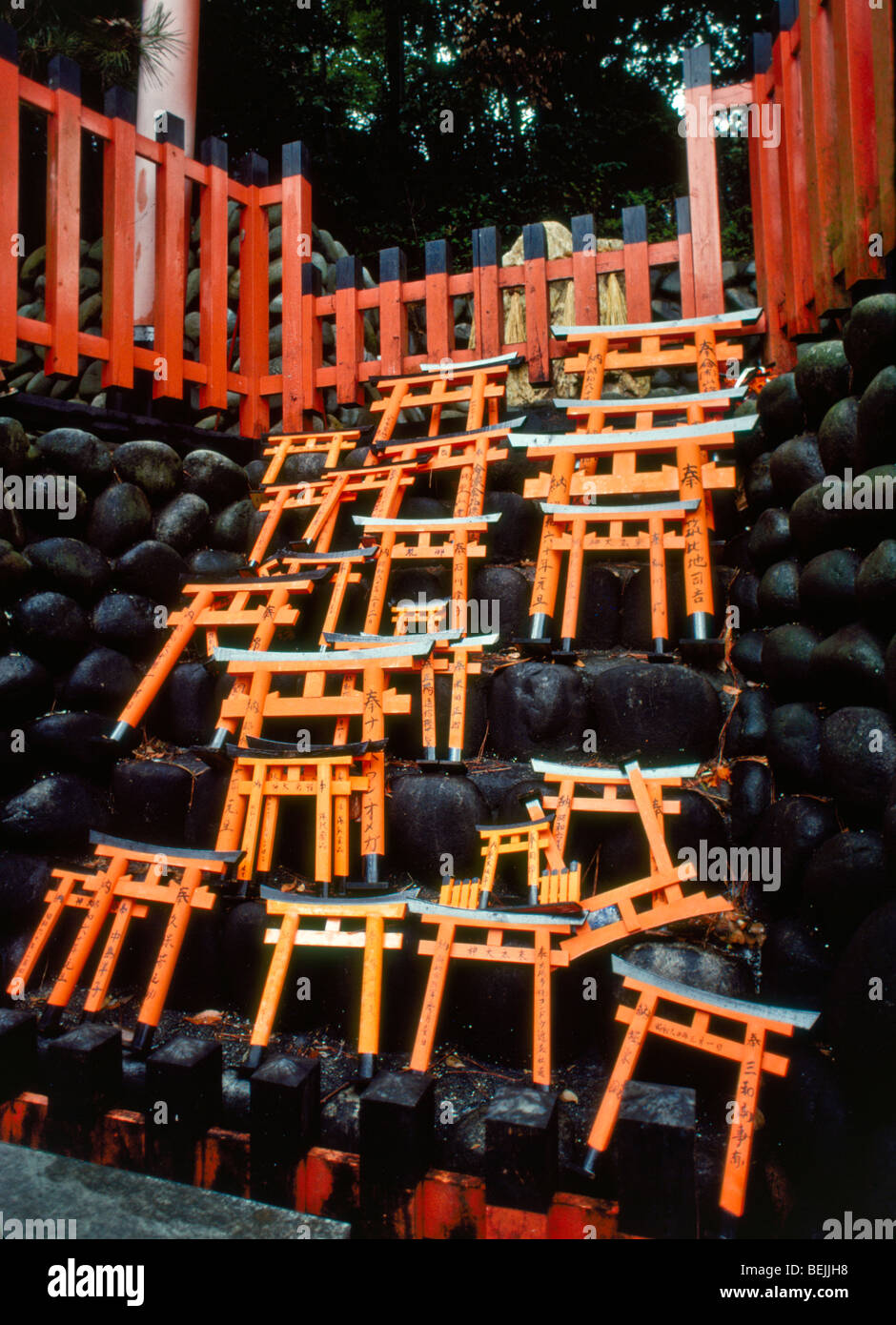 Wood torii (gates) stacked behind cemetery gravestones at Fushimi Inari ...