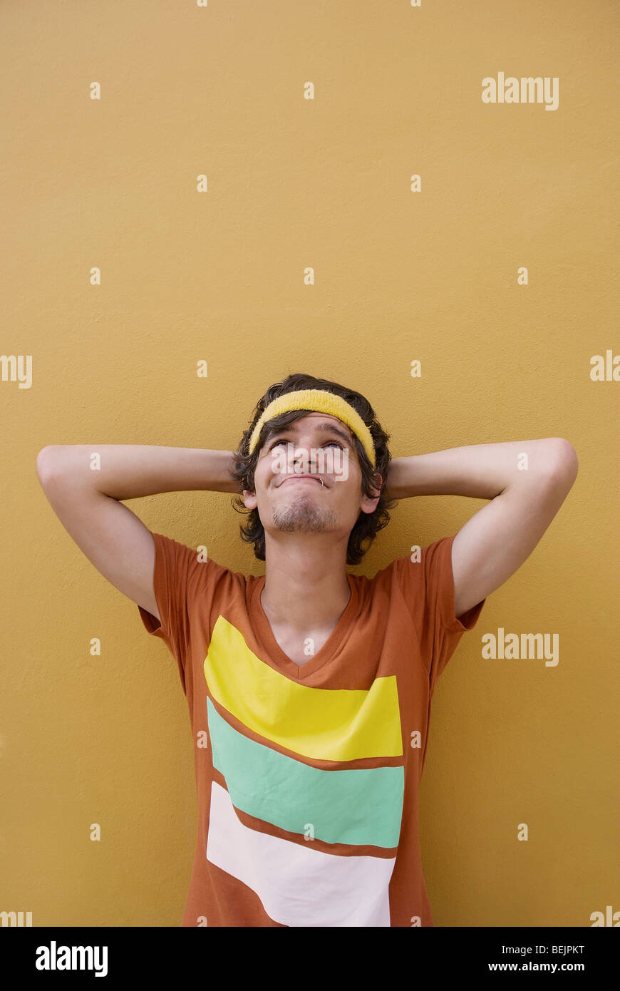 Young man leaning against a wall with his hands behind his head Stock ...